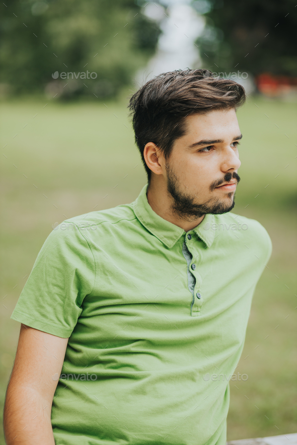 Vertical portrait of a young attractive Caucasian male posing outdoors ...
