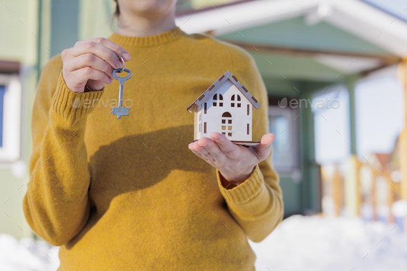 woman holds key and a model of mock-up of house in her hands. sale of ...