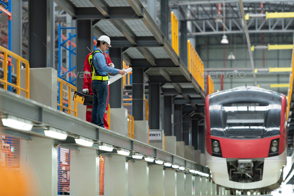 Electric train engineer and technician with tools inspect the railway ...