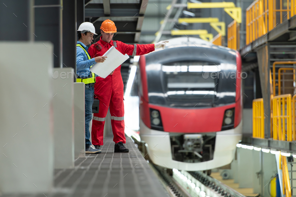 Electric train engineer and technician with tools inspect the railway ...