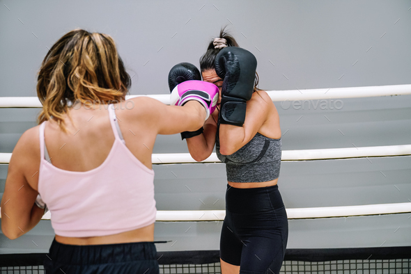 Female boxer punching her opponent while she covers herself in a ...
