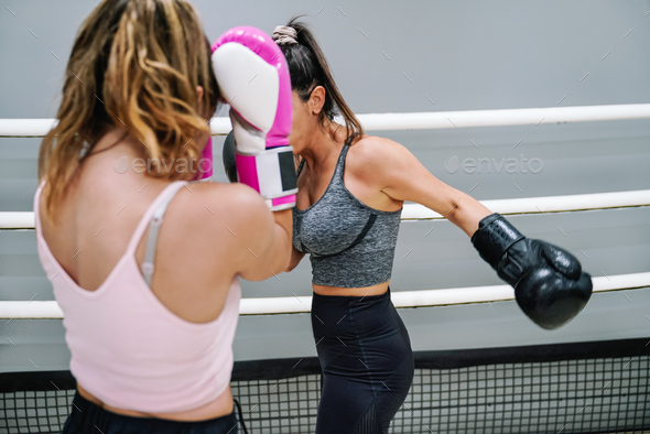 Female boxer throwing a side punch to her opponent in a practice in the ...