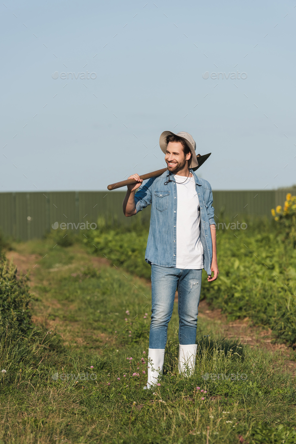 full length view of young farmer with shovel smiling in field Stock ...