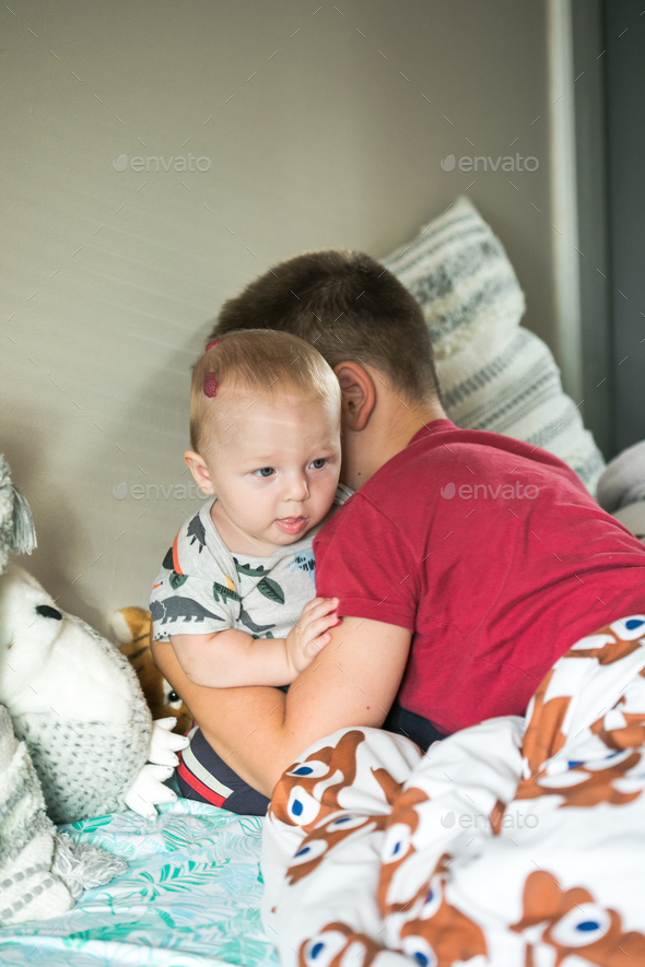 Older brother hugs baby. Cute boy and his brother relaxing in a white ...