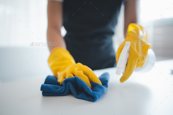 Cleaning desk surface in office with sanitizer spray, wear gloves and ...