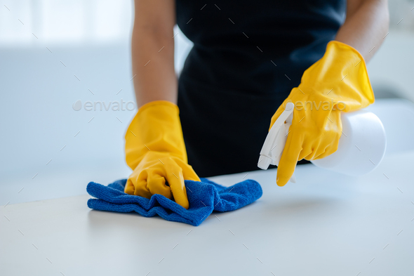 Cleaning desk surface in office with sanitizer spray, wear gloves and ...