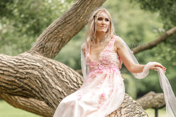 A young girl with blond hair in a pink dress.Beautiful medieval elven ...