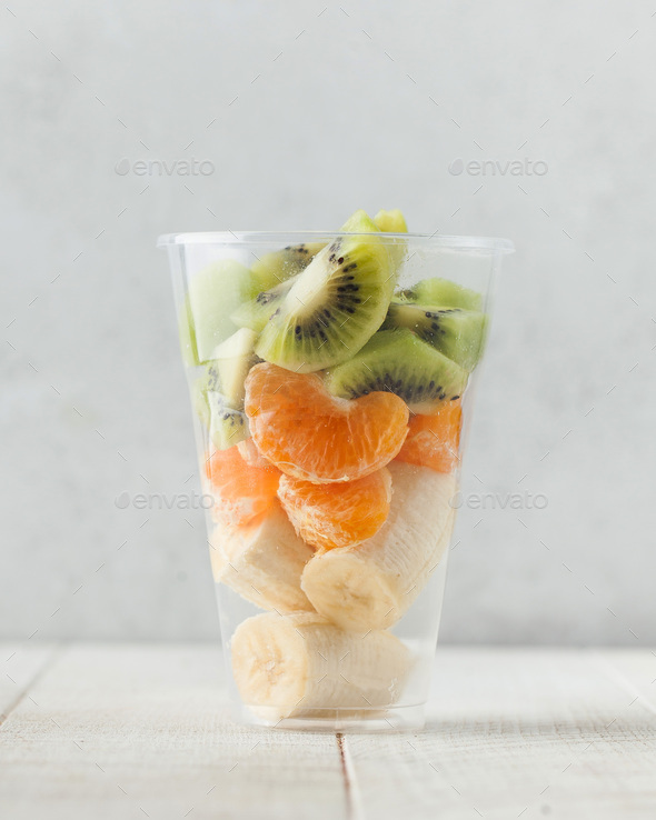 Slices of tangerine, banana and kiwi in a clear glass. Fruit salad ...