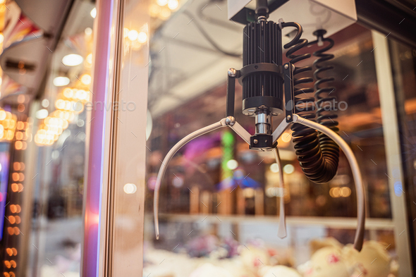 Close-up of the claw machine arcade game in an evening amusement park ...