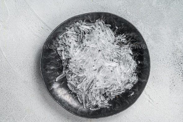 Menthol Crystals in a steel small plate. White background. Top view ...