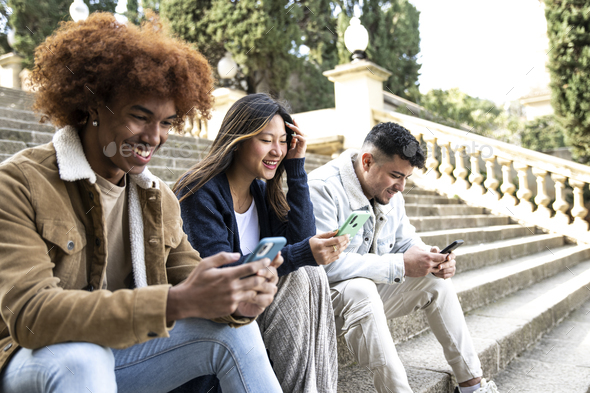 Three young diverse people texting with smartphones sitting on the ...
