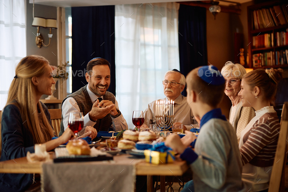 Happy Jewish man communicating with his extended family at dining table ...