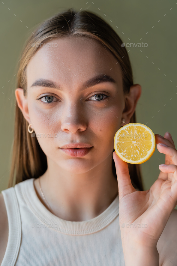 portrait of pretty young woman showing half of juicy lemon isolated on ...