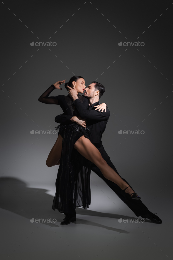 Side view of professional dancers performing tango on grey background ...