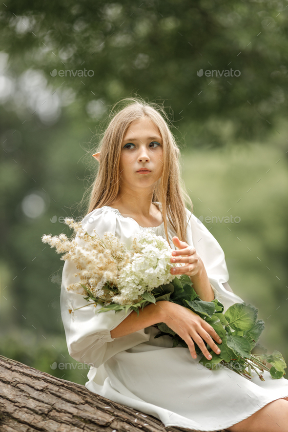 A young elf girl with blond hair with a bouquet of flowers.medieval ...