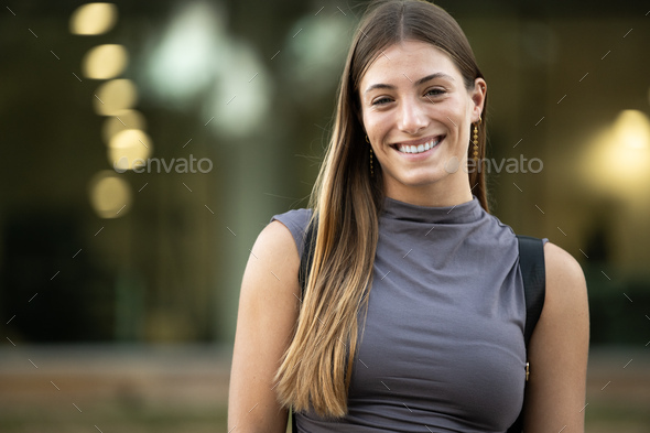 Beautiful cheerful young lady looking at camera standing outside.Joyful ...