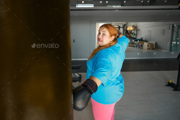 Concentrated fat woman using boxing gloves doing punching exercises ...