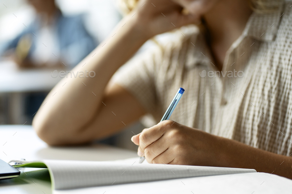 Closeup of school girl hand taking notes learning language in classroom ...