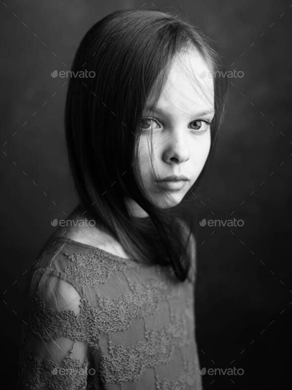Portrait of a little girl in a dress on a dark gray background ...
