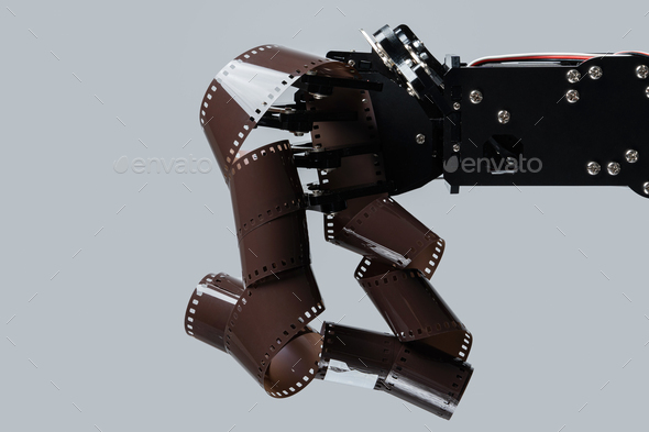 Real robotic hand with film stock. Concept of AI in motion picture and ...