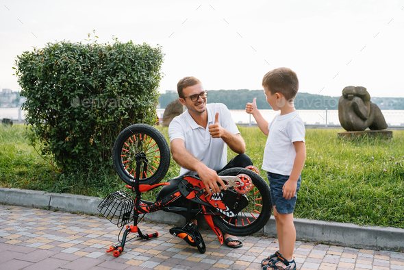 Happy father and his son having fun together at the green park, fixing ...