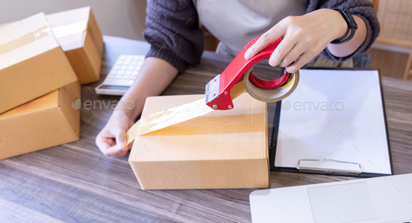 Woman use scotch tape to attach parcel boxes to prepare goods for the ...