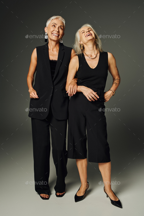 full length of excited mature ladies in black classic attire standing ...