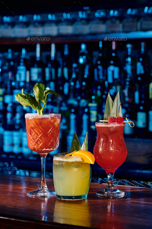 three sophisticated cocktails with fresh decorations on bar counter ...