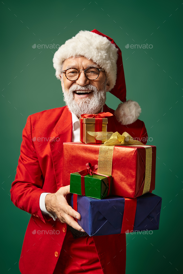 portrait of elegant Santa in red attire holding bunch of presents ...