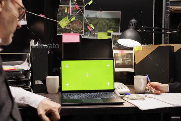 Investigators looking at laptop with green screen display Stock Photo ...