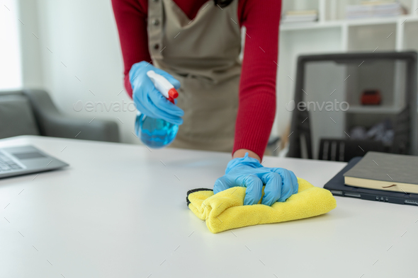 Cleaning desk surface in office with sanitizer spray, wear gloves and ...