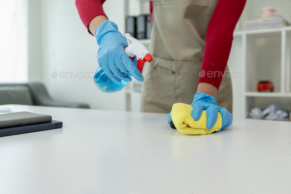 Cleaning desk surface in office with sanitizer spray, wear gloves and ...