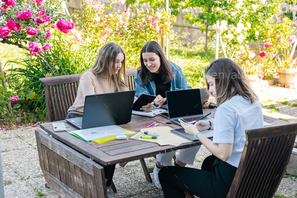 Three university college students studying in the garden at home ...
