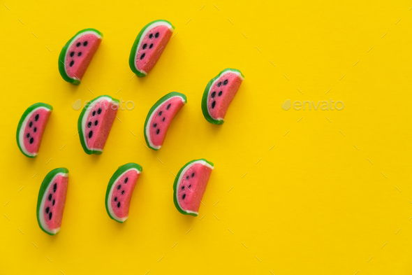 Top view of sweet candies in watermelon shape on yellow background ...