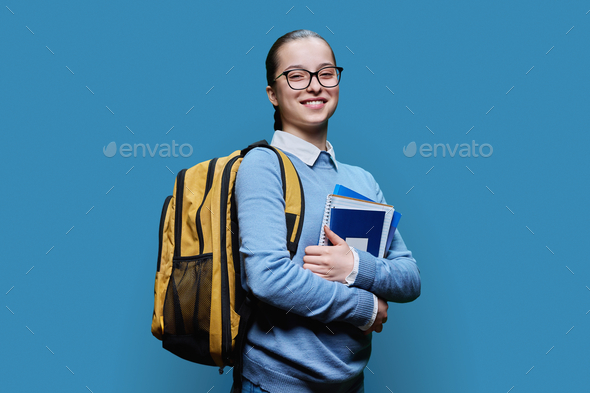 Portrait of teen girl high school student on blue studio background ...