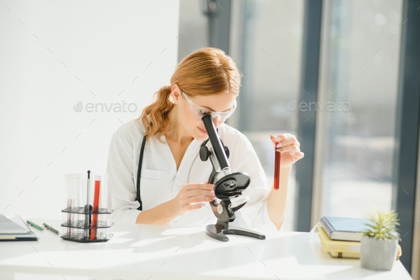 Doctor woman working a microscope. Female scientist looking through a ...