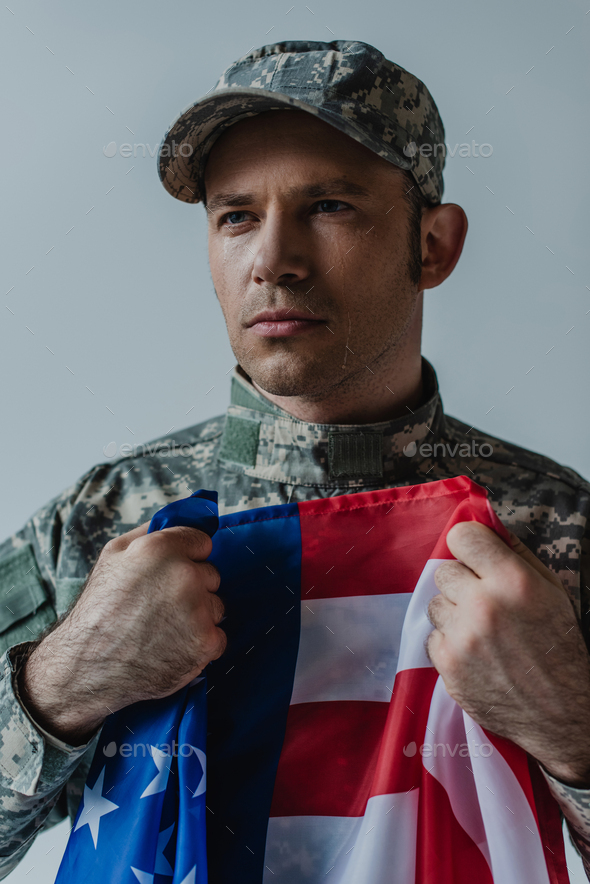 upset American soldier holding flag of United States while crying ...