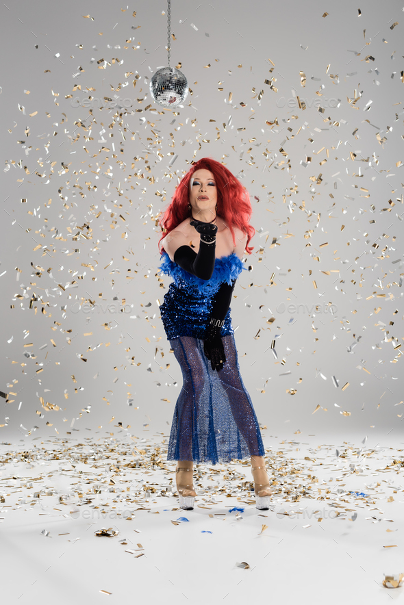 Elegant drag queen in dress and gloves blowing air kiss under disco ...