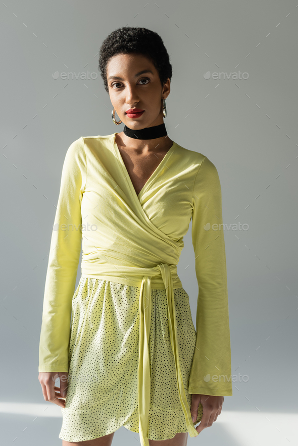 Pretty african american model in spring outfit standing on grey ...