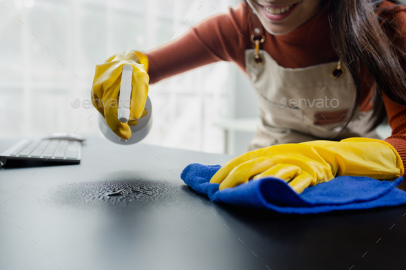 Cleaning desk surface in office with sanitizer spray, wear gloves and ...