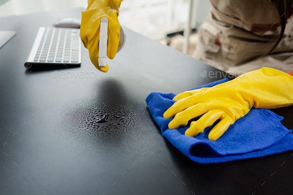 Cleaning desk surface in office with sanitizer spray, wear gloves and ...