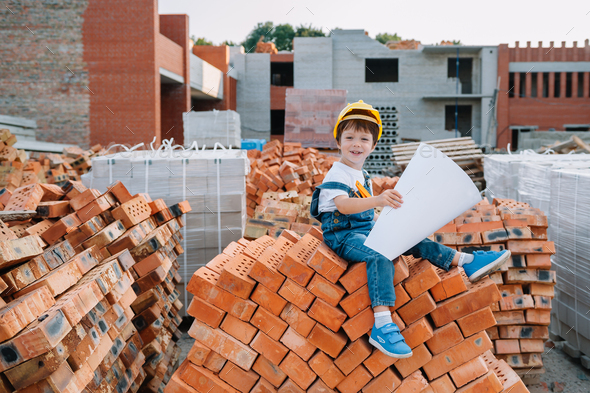 Architect in helmet writing something near new building. boy on the ...