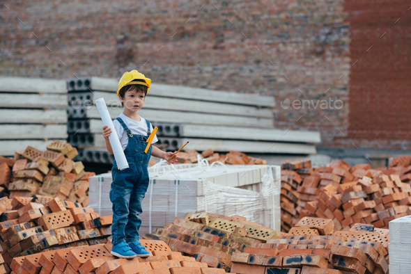 Architect in helmet writing something near new building. boy on the ...