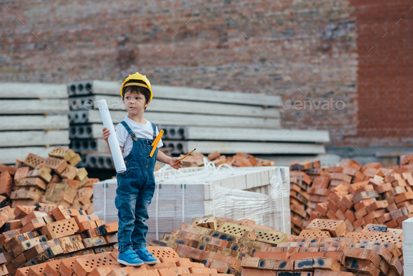 Architect in helmet writing something near new building. boy on the ...