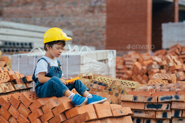 Architect in helmet writing something near new building. boy on the ...