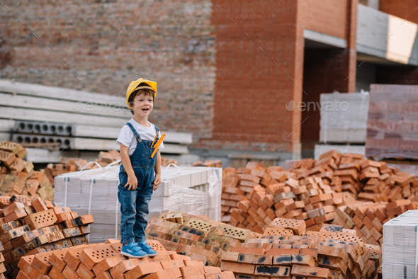 Architect in helmet writing something near new building. boy on the ...
