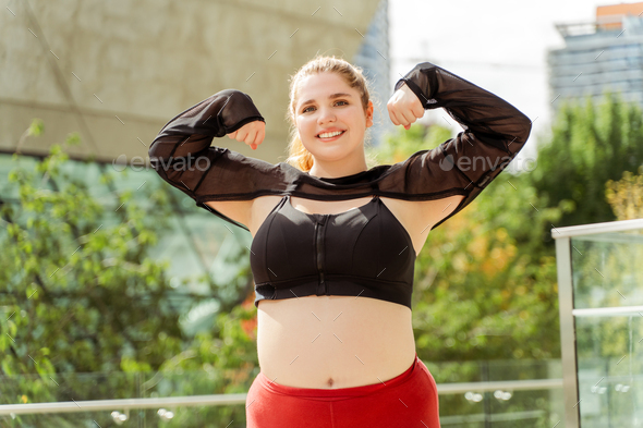 female in activewear showing muscles after intense workout outdoors ...