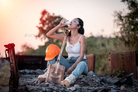 Beautiful woman coal worker showed tried from work sitting on railway ...