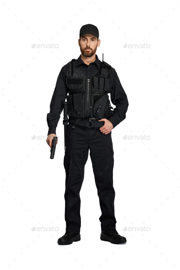 Confident police officer in uniform posing with weapon in studio. Stock ...
