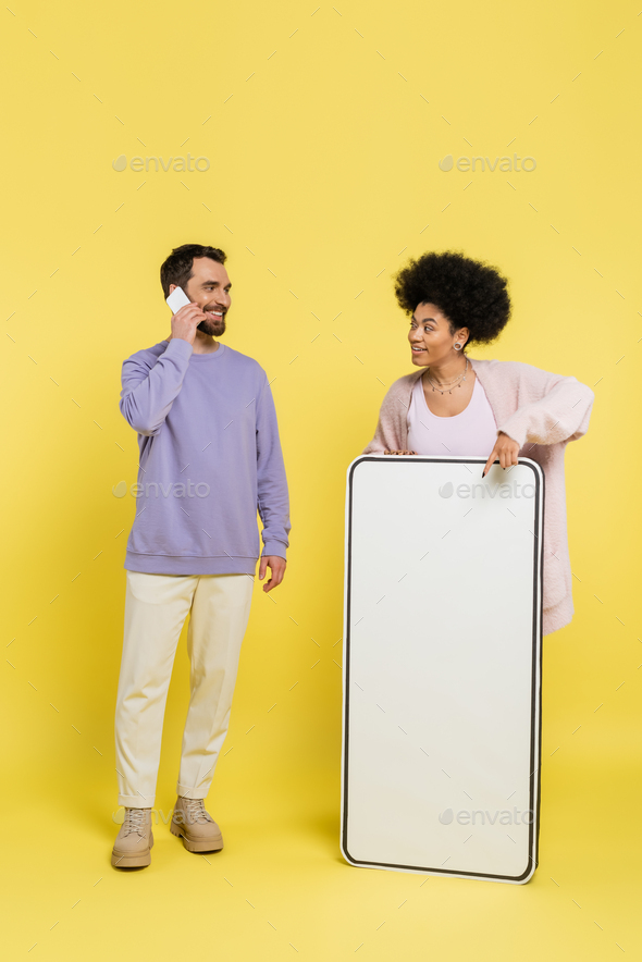 african american woman pointing at phone template near smiling bearded ...